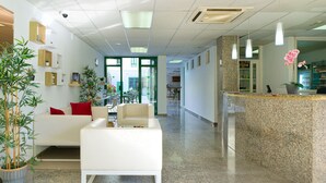 Um lobby moderno com balcão de recepção, área de estar e plantas em vasos.