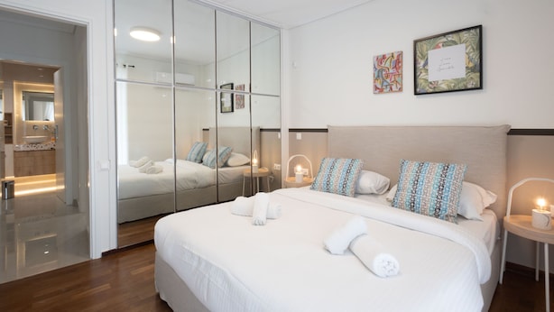 Quarto de hotel moderno com cama grande, closet espaçoso e banheiro com pia e espelho.