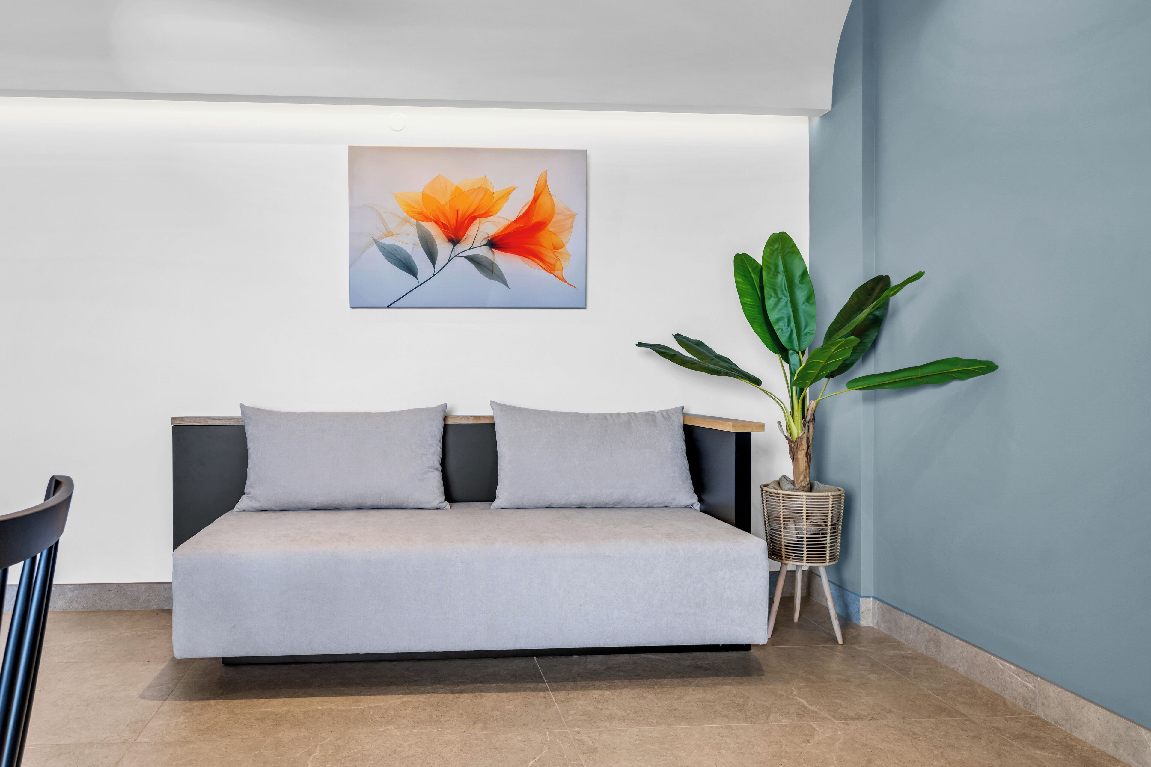 Uma sala de estar moderna com um sofá, uma planta em vaso e um quadro na parede.