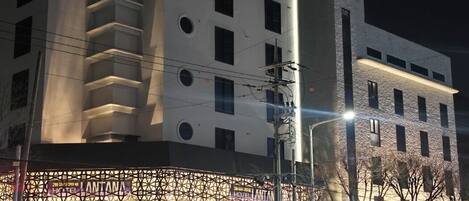Um hotel com fachada moderna, vários andares e sinalização iluminada.
