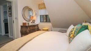 Um quarto com uma cama grande, cômoda, espelho e janela.