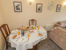 Uma área de refeições com uma mesa posta para o café da manhã, incluindo croissants, frutas e bebidas.