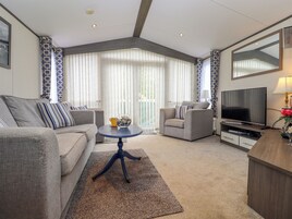 Uma sala de estar moderna com sofá, poltrona e televisão sobre um suporte de madeira.