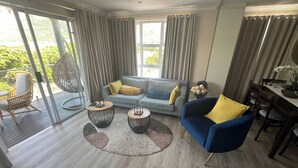 Uma sala de estar moderna com um sofá cinzento, uma poltrona azul e mesas de centro redondas.