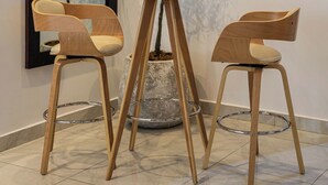 Um interior moderno com uma mesa de madeira redonda, duas cadeiras de madeira e um vaso com planta.