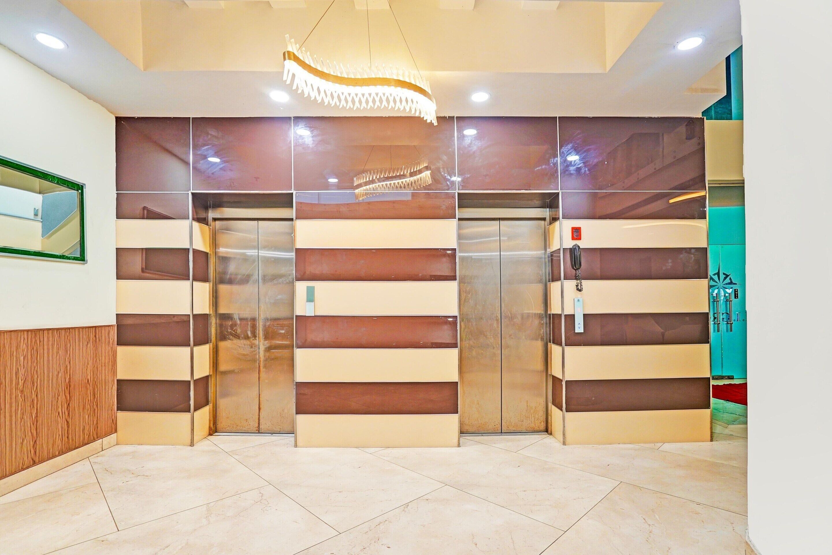Área de elevador moderna com paredes listradas e um lustre pendurado.