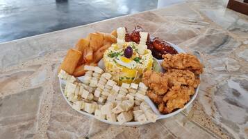 Uma mesa com tampo de mármore e um prato de comida com frango frito, milho e salada.