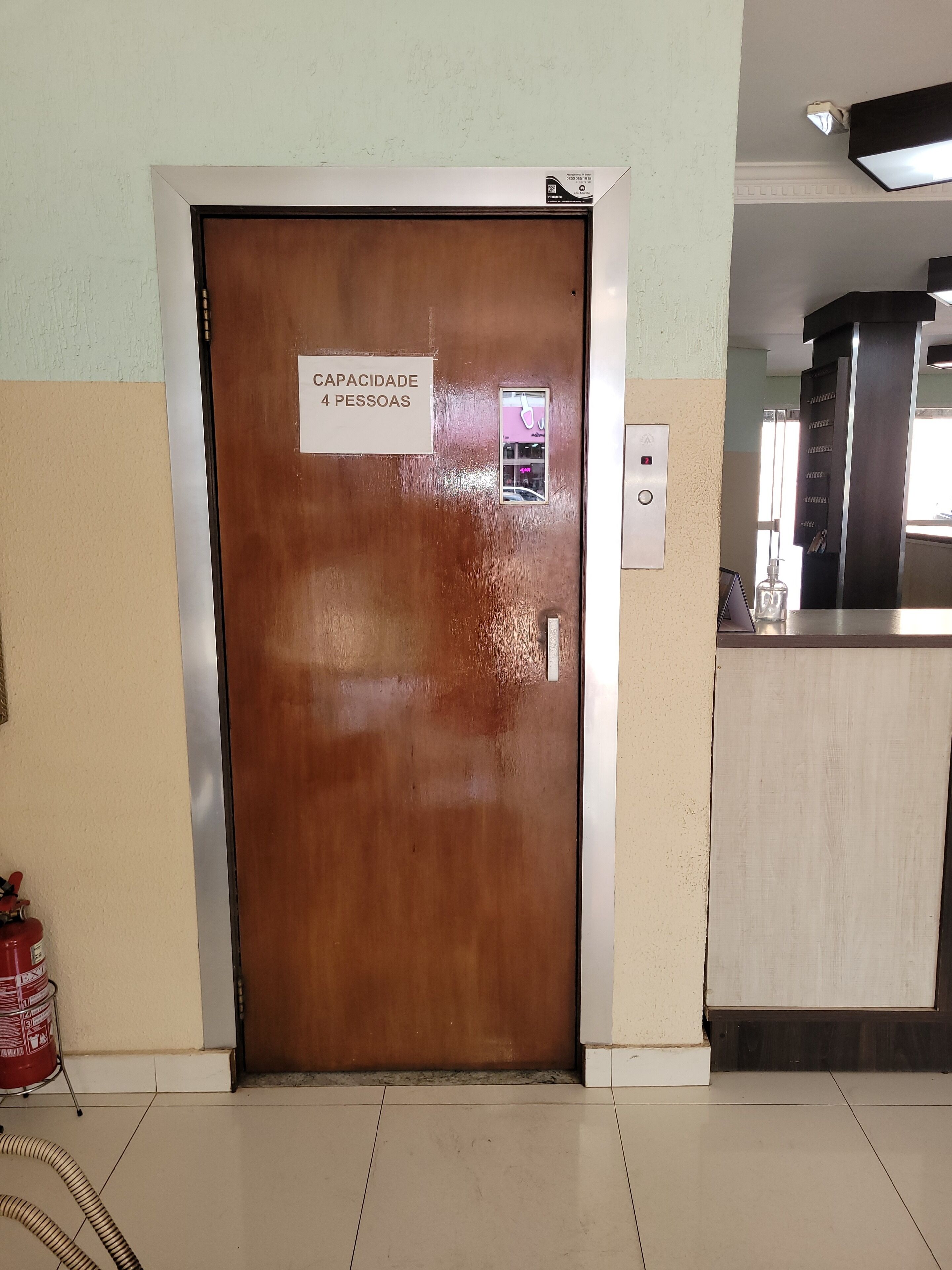 Porta de elevador de madeira com sinal indicando capacidade para 4 pessoas.