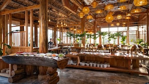 Interior rústico de madeira com uma longa mesa de jantar, luminárias pendentes e janelas grandes.