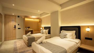 Quarto de hotel moderno com duas camas, um guarda-roupa de madeira, uma mesa de cabeceira e um banco embutido.
