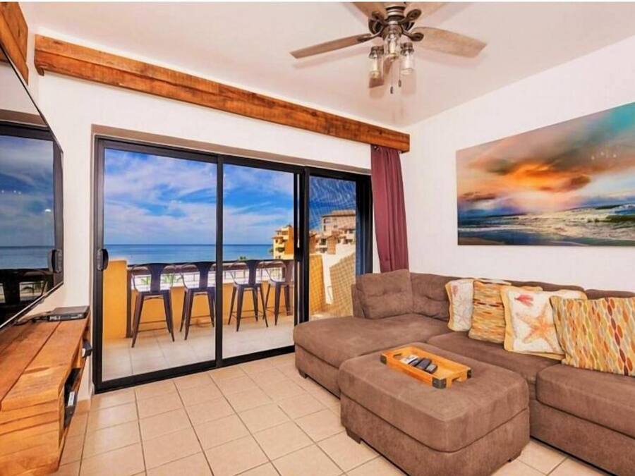 Sala de estar com uma janela grande, ventilador de teto e uma pintura de pôr do sol.