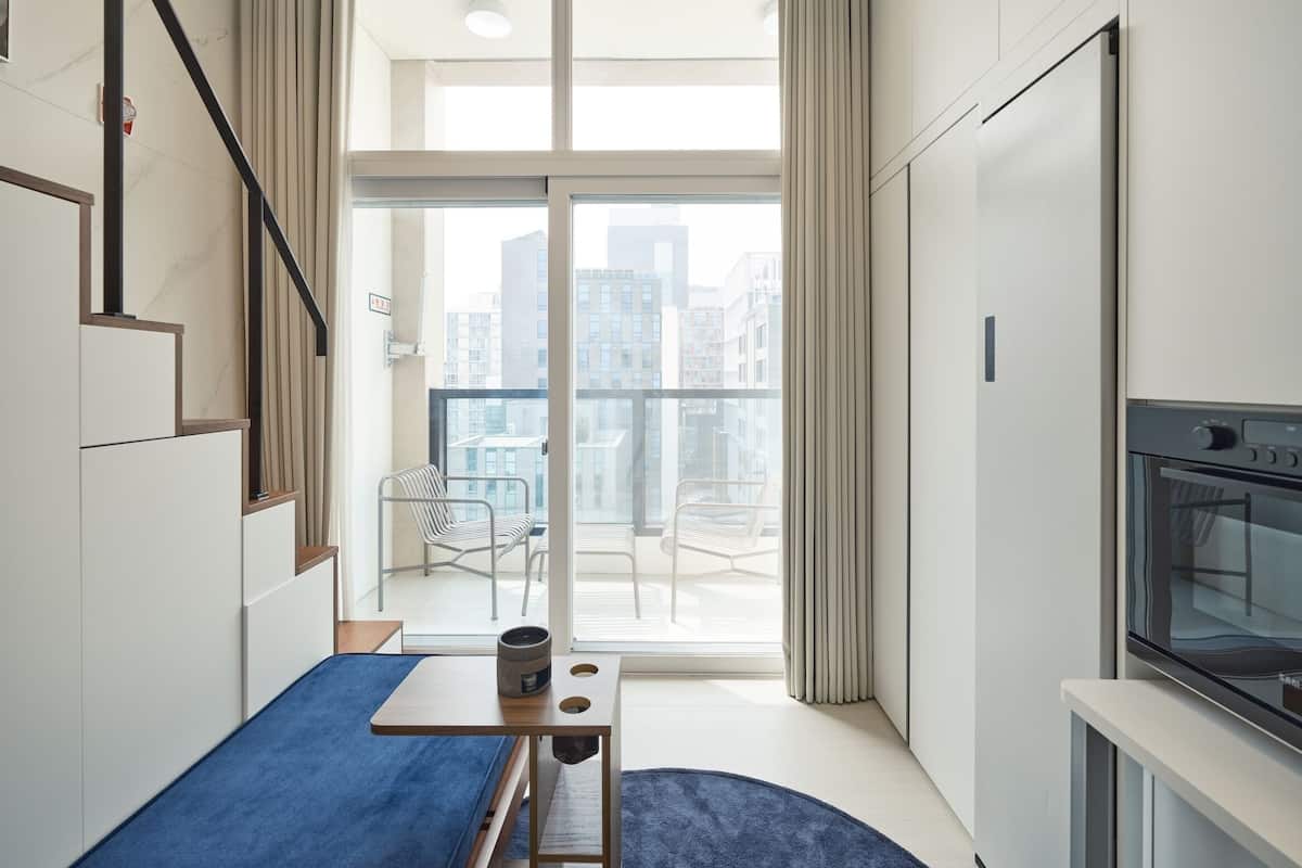 Um apartamento moderno com varanda, pequena cozinha e área de estar com mesa e cadeiras.