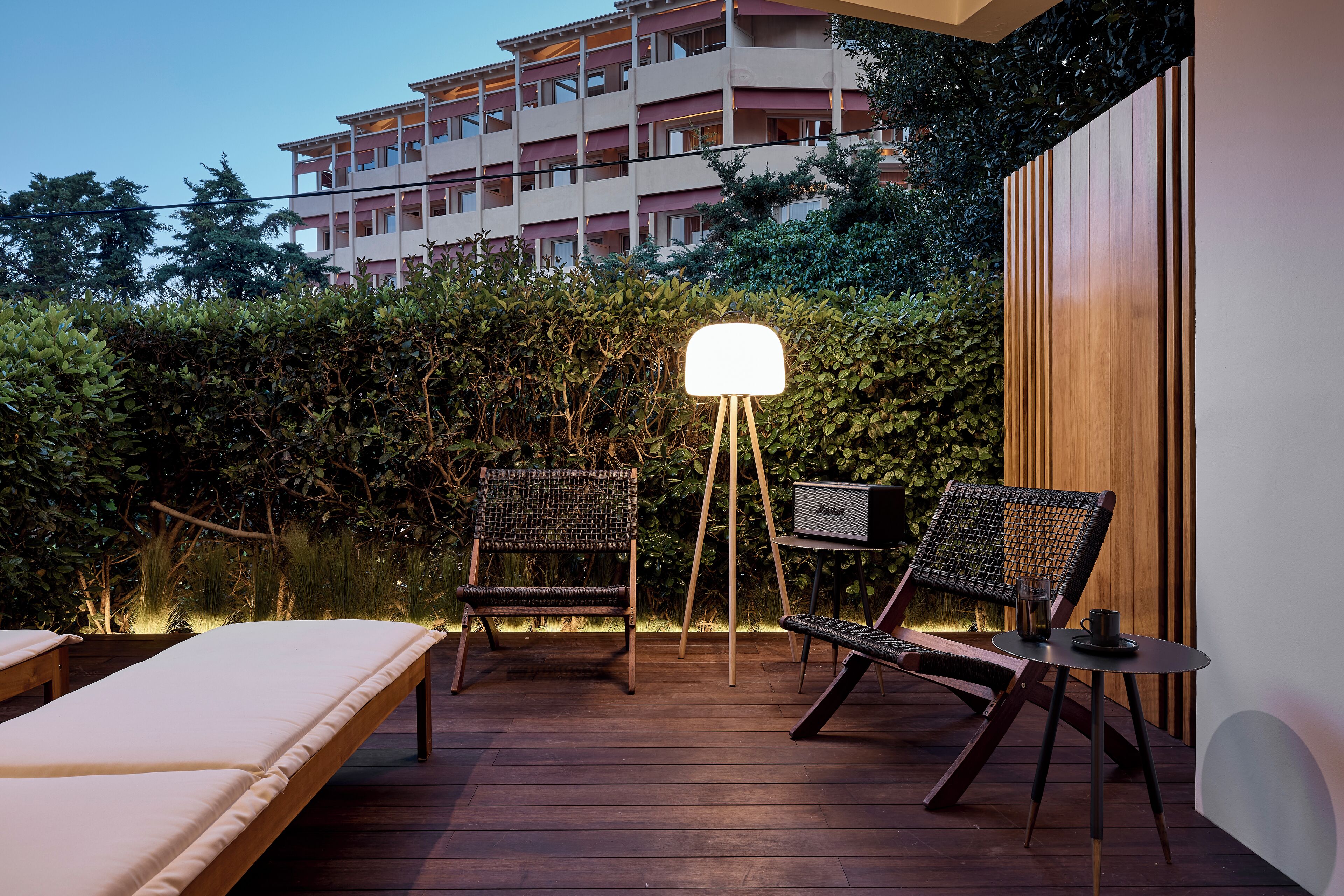 Um terraço com espreguiçadeiras, uma mesa e um abajur.