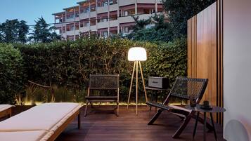 Um terraço com espreguiçadeiras, uma mesa e um abajur.