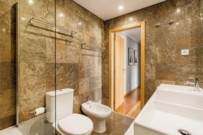 Uma casa de banho moderna com sanita, bidé e uma banheira grande.