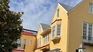 Um edifício amarelo com telhado vermelho, cerca branca de piquete e placa indicando espaço para dois veículos.