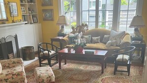 Uma sala de estar aconchegante com um sofá, cadeiras, uma mesa de centro e um tapete estampado.