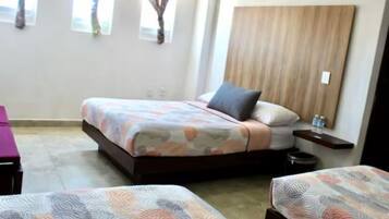 Quarto de hotel com uma cama, duas mesas de cabeceira, cortinas numa janela e vista para o exterior.