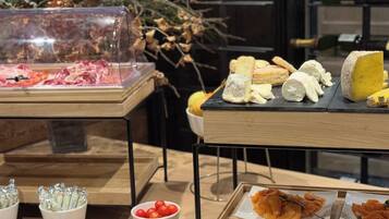 Buffet com diversos alimentos, incluindo queijos, carnes e frutas.