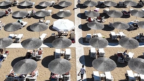 Uma praia com vários guarda-sóis e espreguiçadeiras, um deque de madeira e uma placa com a inscrição 'COPPA French Riviera Club'.