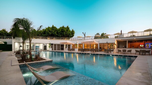 Piscina com espreguiçadeiras, restaurante e área externa para refeições.