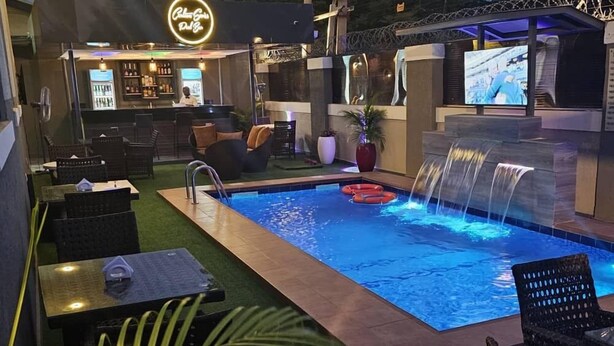 Uma área de piscina interna com bar, assentos e uma cascata.