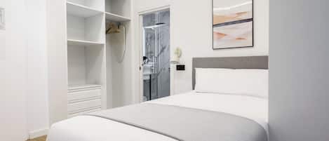 Quarto moderno com cama grande, closet espaçoso e chuveiro.