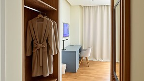 Quarto de hotel moderno com guarda-roupa de madeira, secretária com computador e vista para o exterior.
