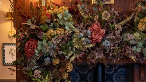Lareira com mantelo decorado com flores e um quadro emoldurado.