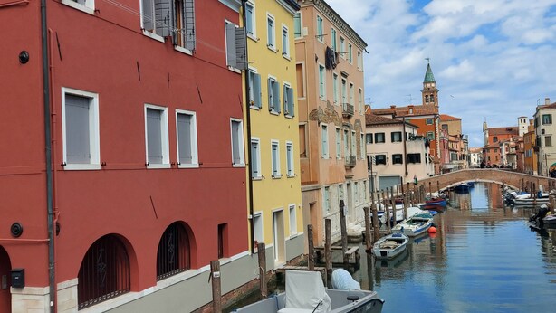 Um canal com edifícios coloridos e um barco atracado na margem.