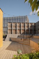 Um deck de madeira com escadas que levam a um edifício moderno com grandes janelas.