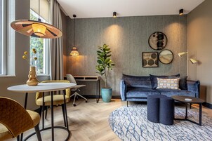 Uma sala de estar moderna com um sofá, uma mesa de centro redonda e uma planta em vaso.