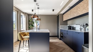 Cozinha moderna com ilha central, iluminação pendente e vista para o exterior.
