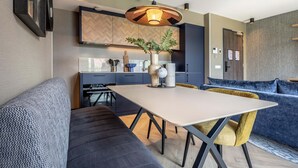 Uma cozinha moderna com área de jantar, apresentando uma mesa grande, cadeiras e um lustre.