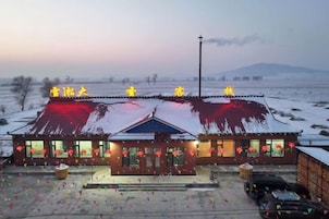 Um edifício com telhado vermelho e letreiros iluminados, rodeado de neve.