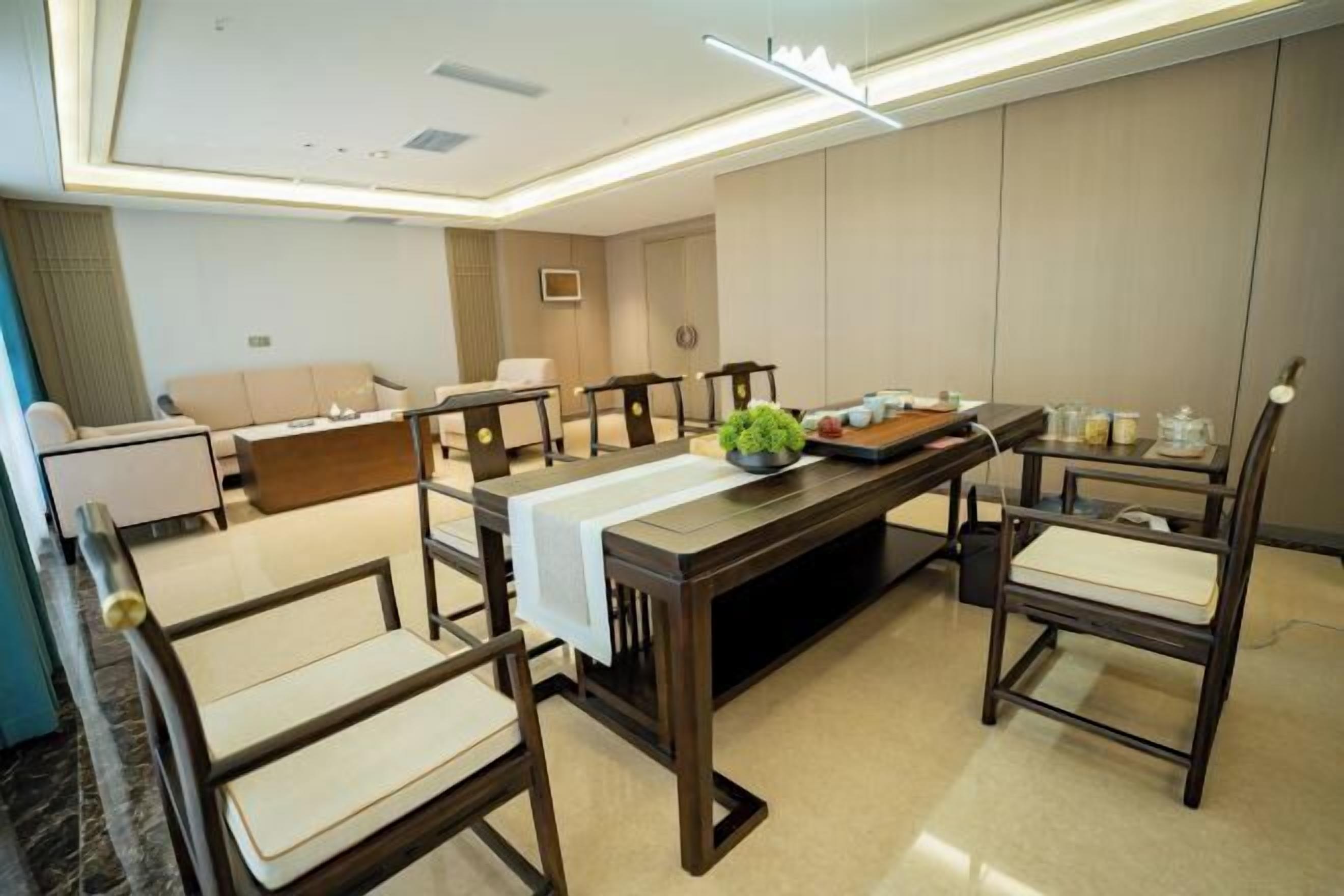 Uma área de jantar moderna com uma mesa comprida, cadeiras e um pequeno arranjo de plantas.