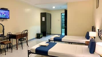 Quarto de hotel com duas camas, uma mesa com cadeiras, uma televisão e um armário.