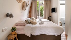 Um quarto com uma cama, uma televisão e uma janela com cortinas.