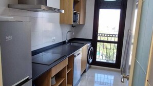 Cozinha moderna com forno embutido, micro-ondas e pia. Há uma janela com vista para o exterior.