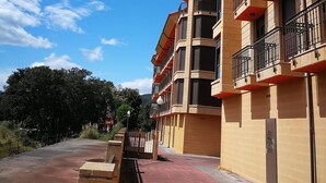 Um edifício de vários andares com varandas, um caminho pavimentado e um céu azul claro.