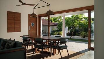 Uma sala de jantar moderna com uma mesa e cadeiras de madeira, um sofá verde e um ventilador de teto.