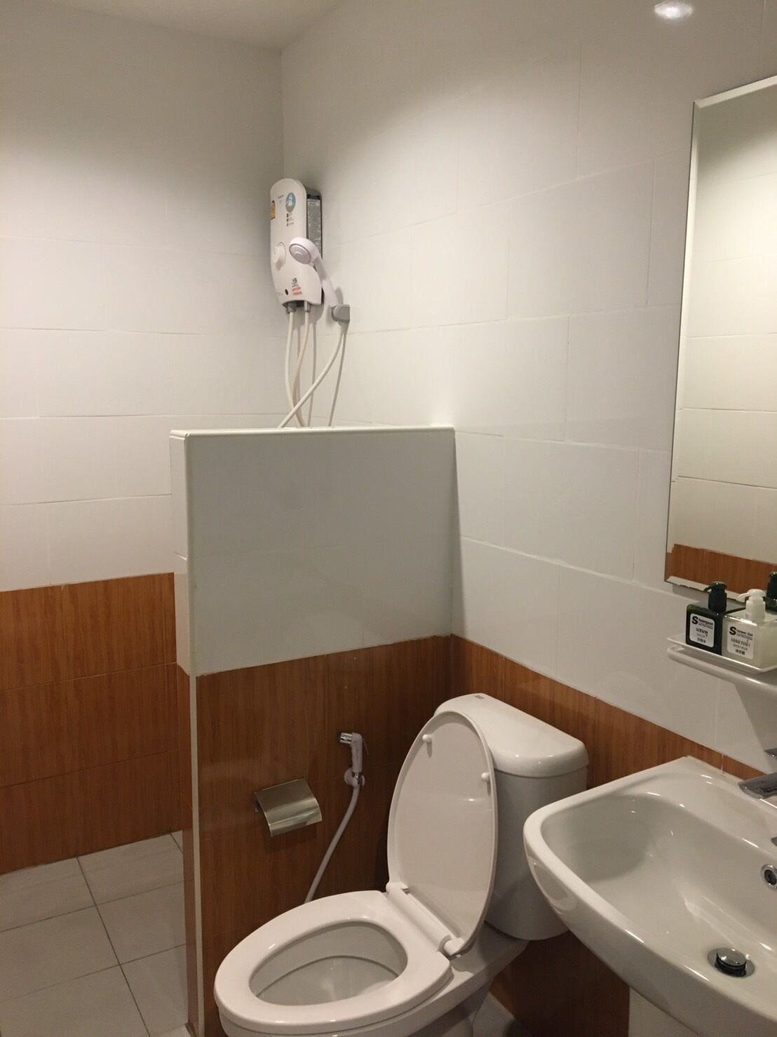 Casa de banho com sanita branca, lavatório e secador de mãos fixado na parede.