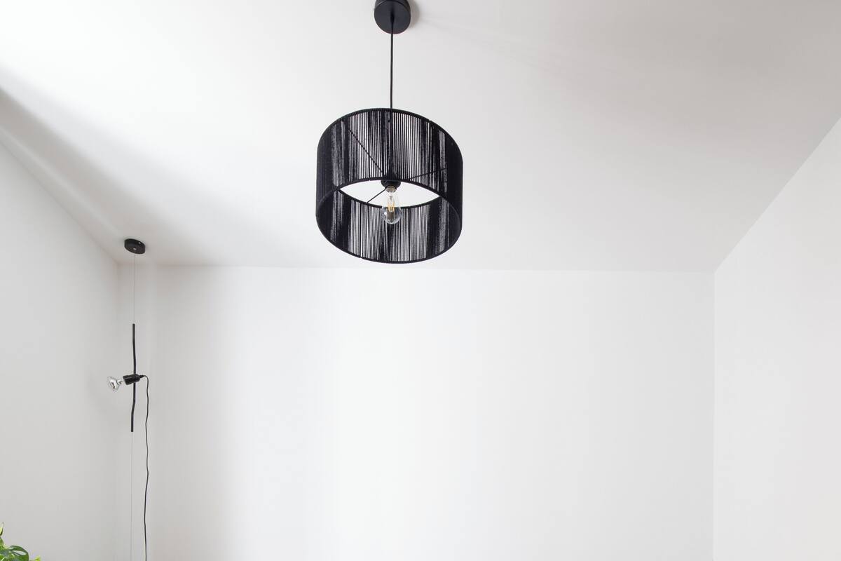 Quarto com sofá verde, mesa de jantar de madeira e luminária pendente preta.