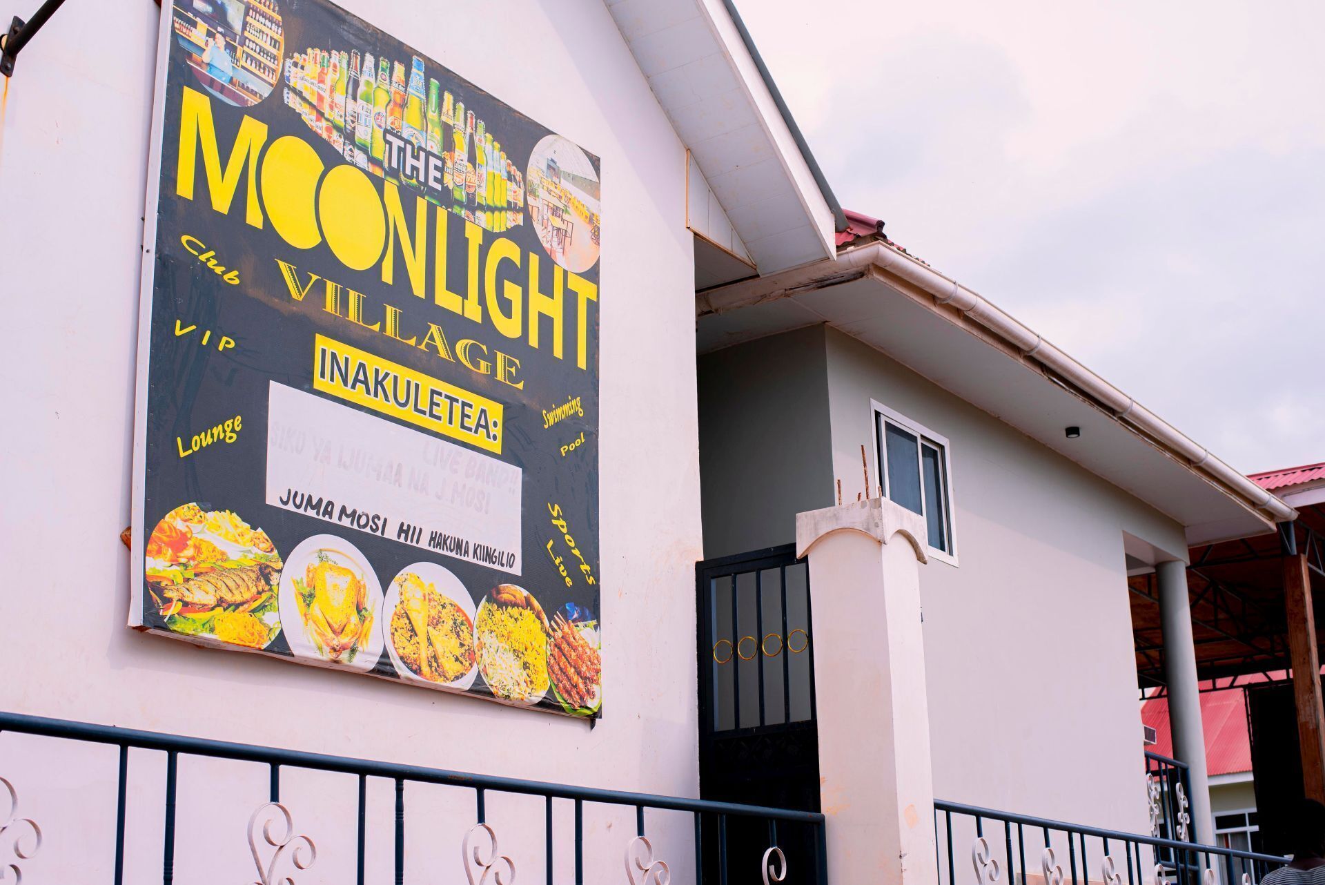 Um edifício com uma placa anunciando 'The Moonlight Village' e 'Inakuletea Lounge'.