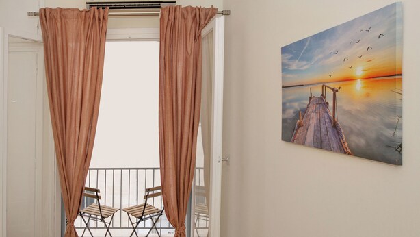 Uma varanda com duas cadeiras, uma pintura de um pôr do sol e vista do céu.