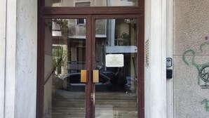 Entrada de um edifício com porta de vidro e uma placa acima.