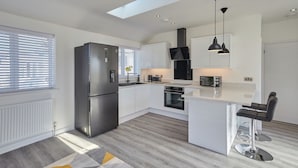 Cozinha moderna com ilha central, eletrodomésticos de aço inoxidável e iluminação pendente.