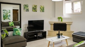 Uma sala de estar com televisão de tela plana, lareira e sofá.