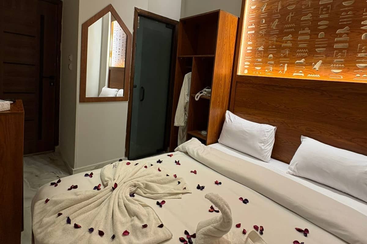 Quarto de hotel com cama, guarda-roupa, espelho e parede com padrões entalhados.