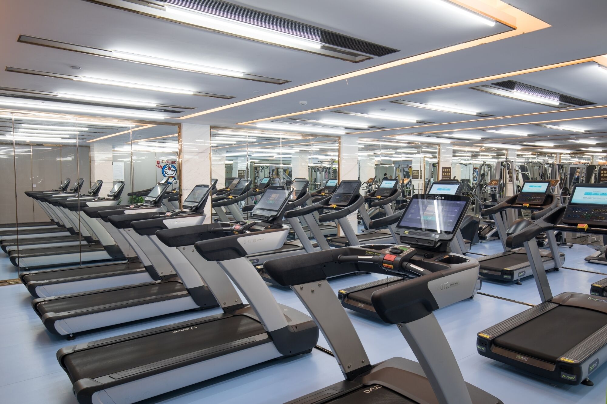 Uma academia com várias esteiras e equipamentos de ginástica.